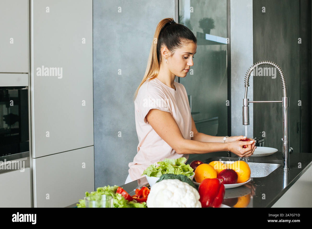 Young woman washes vegetables in the kitchen Stock Photo - Alamy