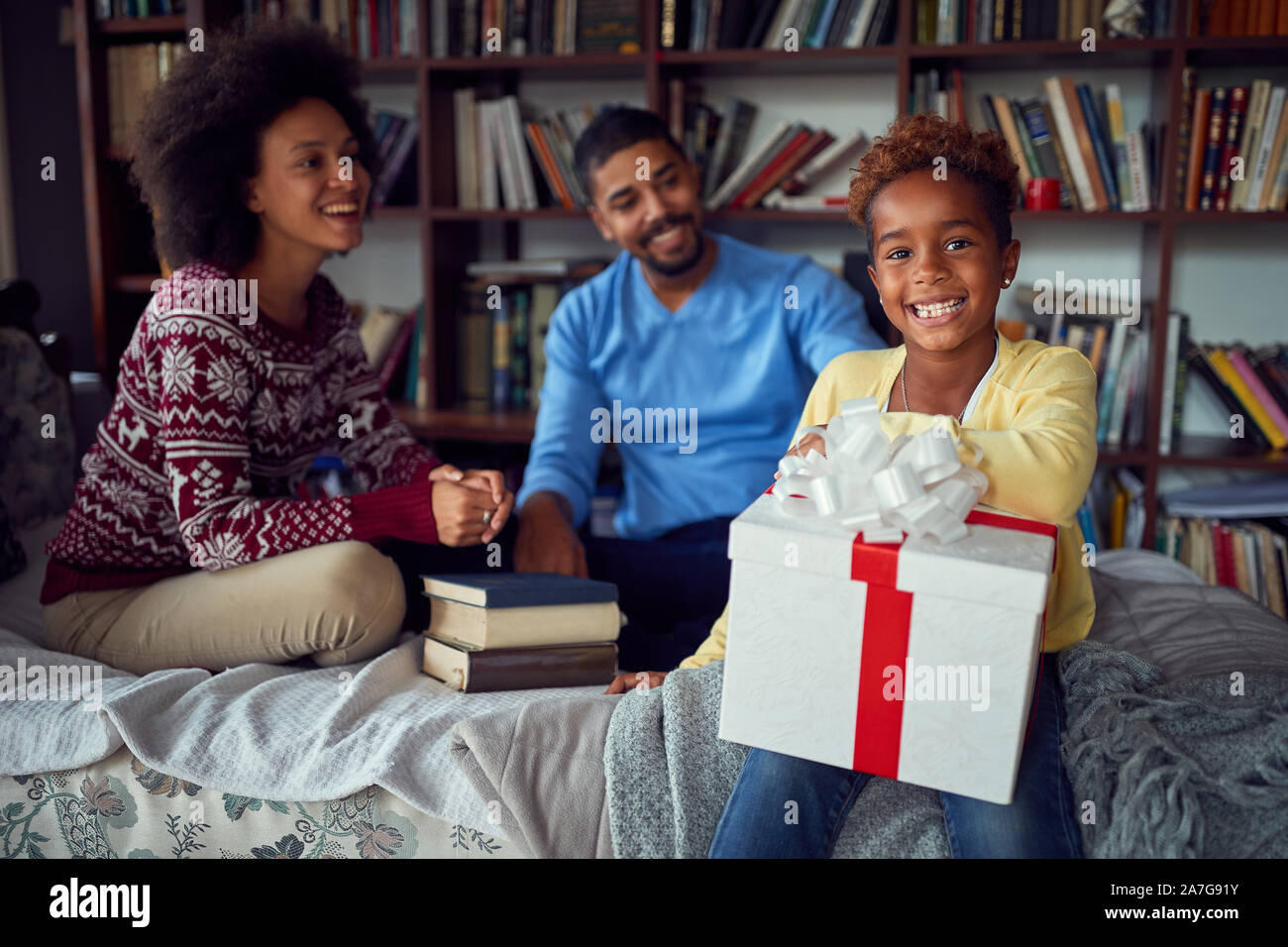 Smiling parents surprising happy daughter with a Christmas present ...