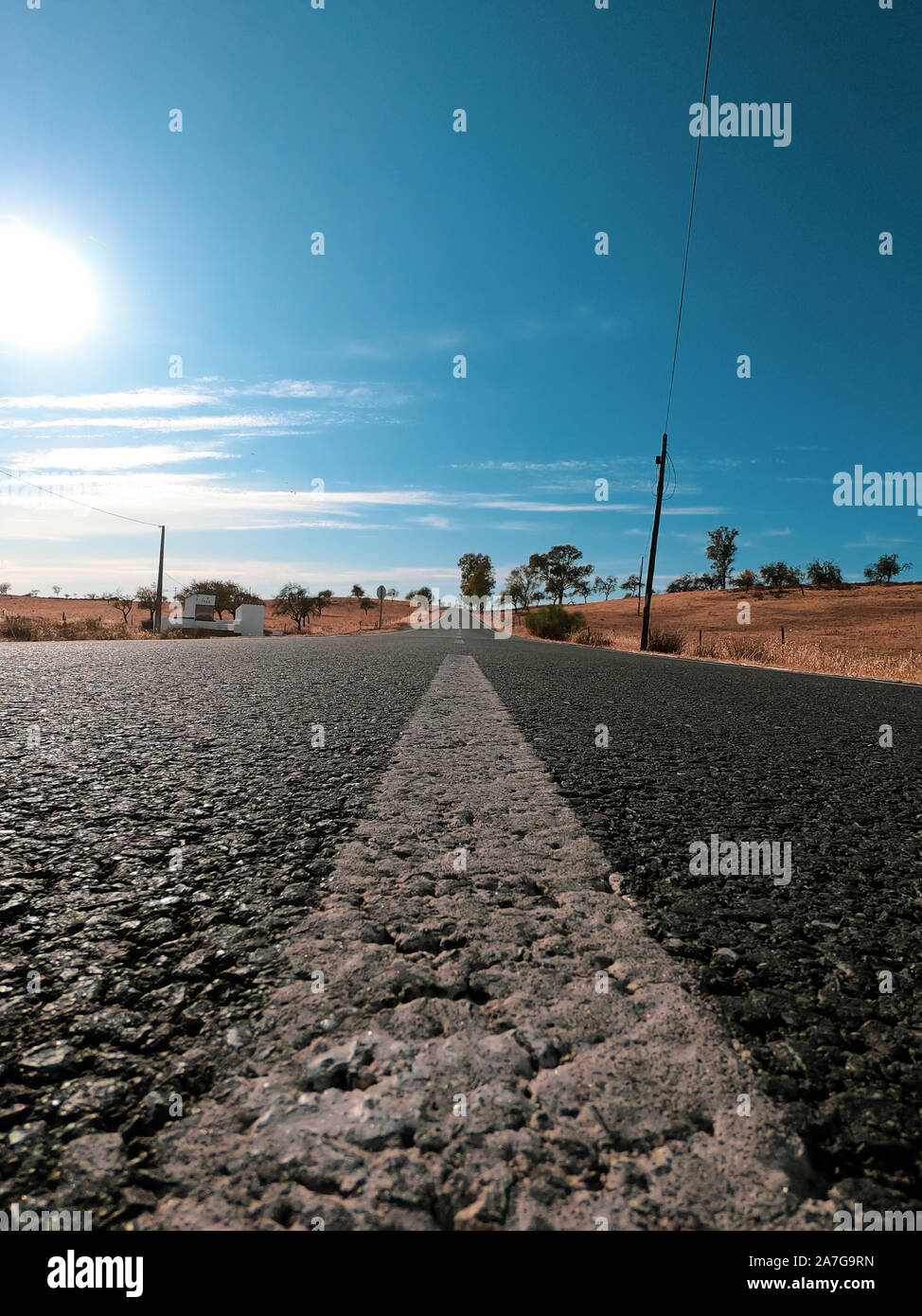 asphalt road in a dry countryside with blue sky in background Stock ...