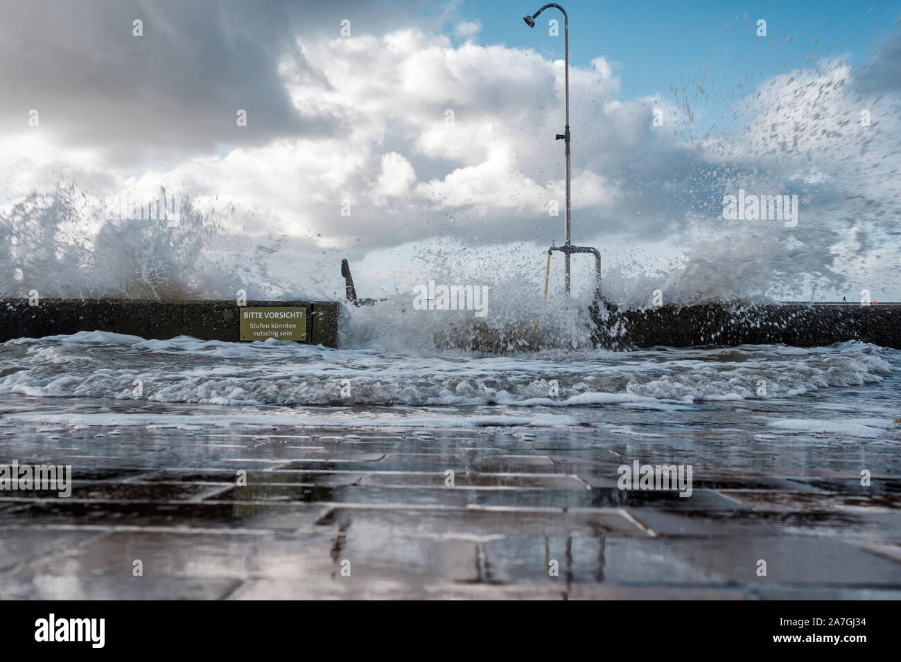 Splash of a wave on the flooded embankment near sea. It is written in ...