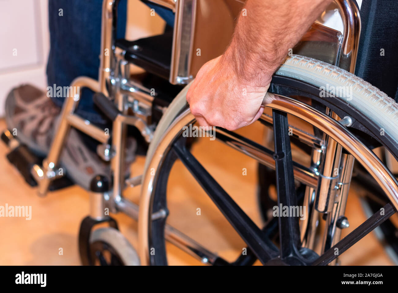 Close up of handicapped man's hand pushing wheel of wheelchair ...