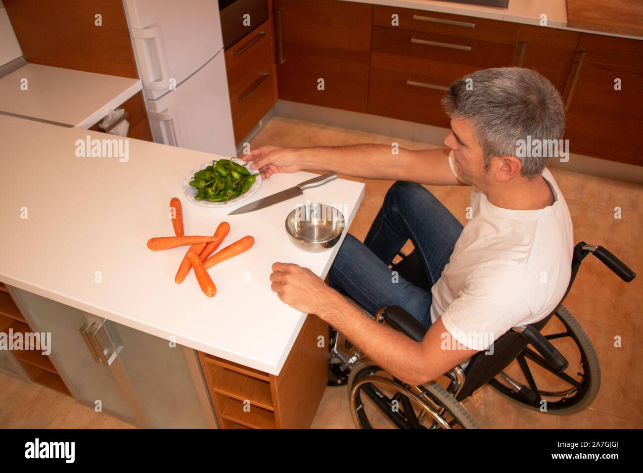 A man in a wheelchair preparing food in the kitchen. Disability concept ...