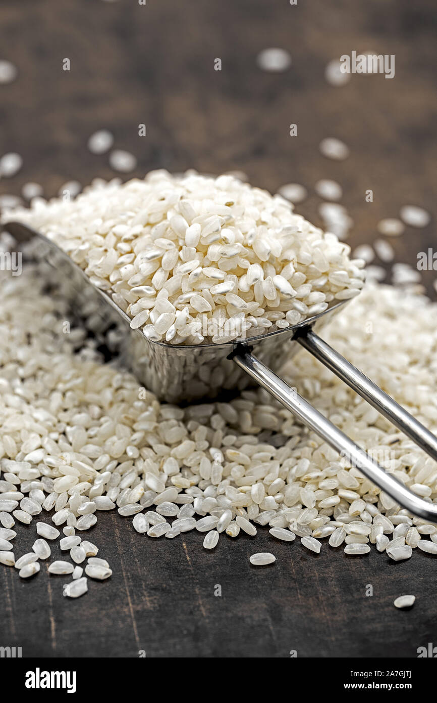 raw rice grains in a metal shovel and scattered on a stone plate Stock ...