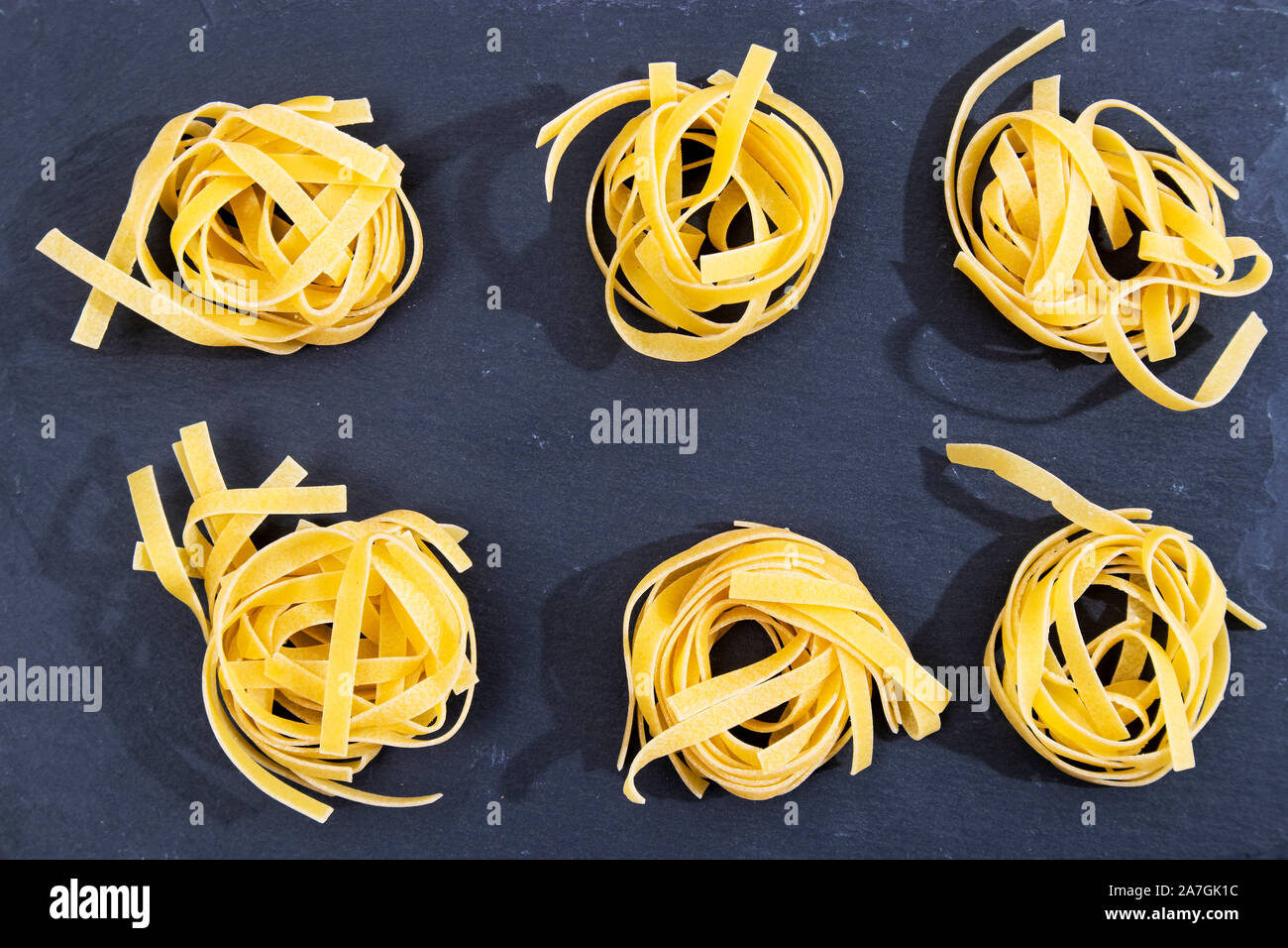 Pasta nests on the black stone board ready to cook and taste with the ...