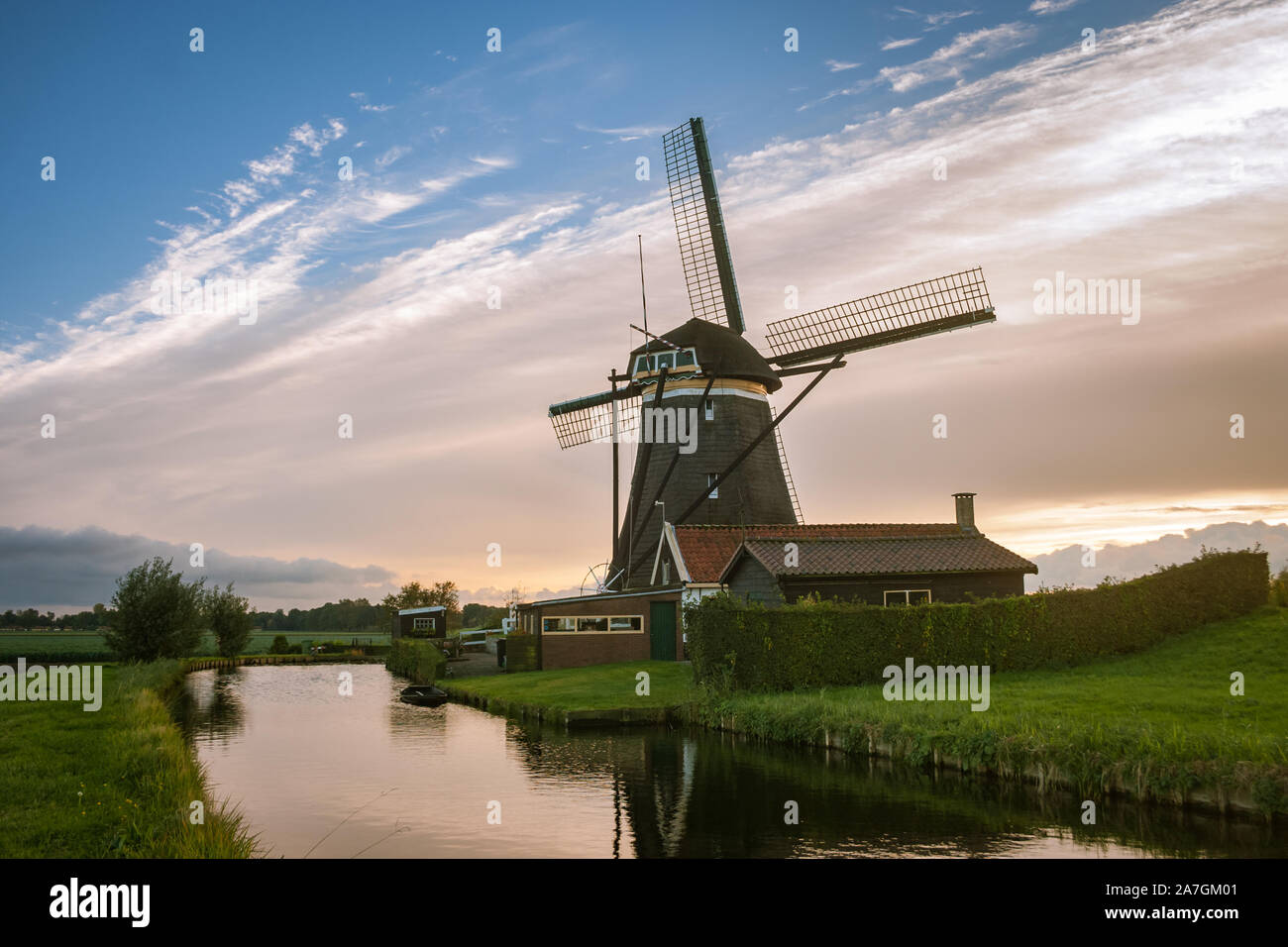 Classic scene of a dutch windmill and house near a canal with a great ...