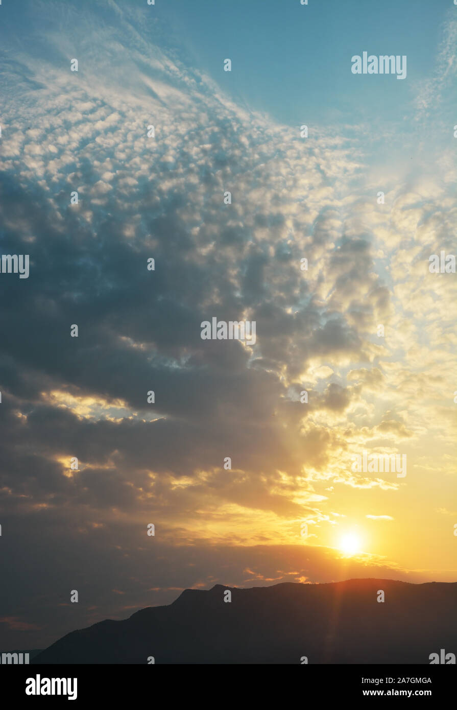 Sun shining through dramatic cloudscape over the mountain Stock Photo ...