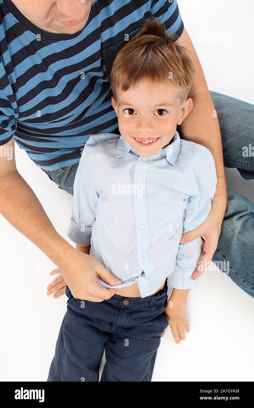 Gorgeous little boy lying in his dad's lap getting tickled and giggling ...