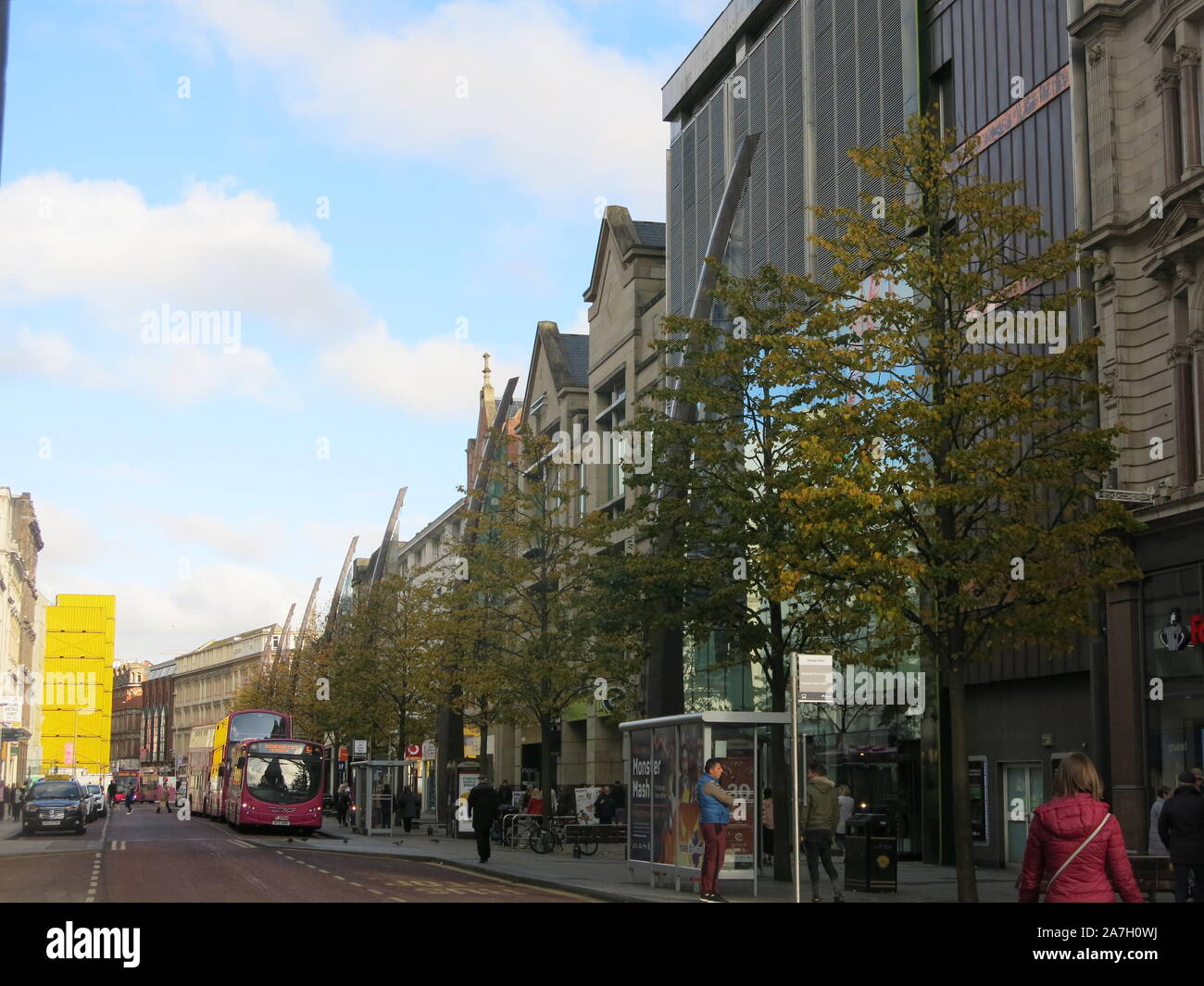Photo of shopfronts, buses, tall trees, pedestrians and Titanic banners ...