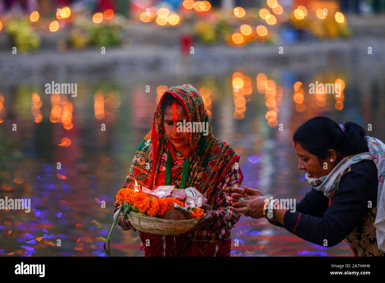 A hindu devotee stands at the Bagmati river to offer prayers to setting ...
