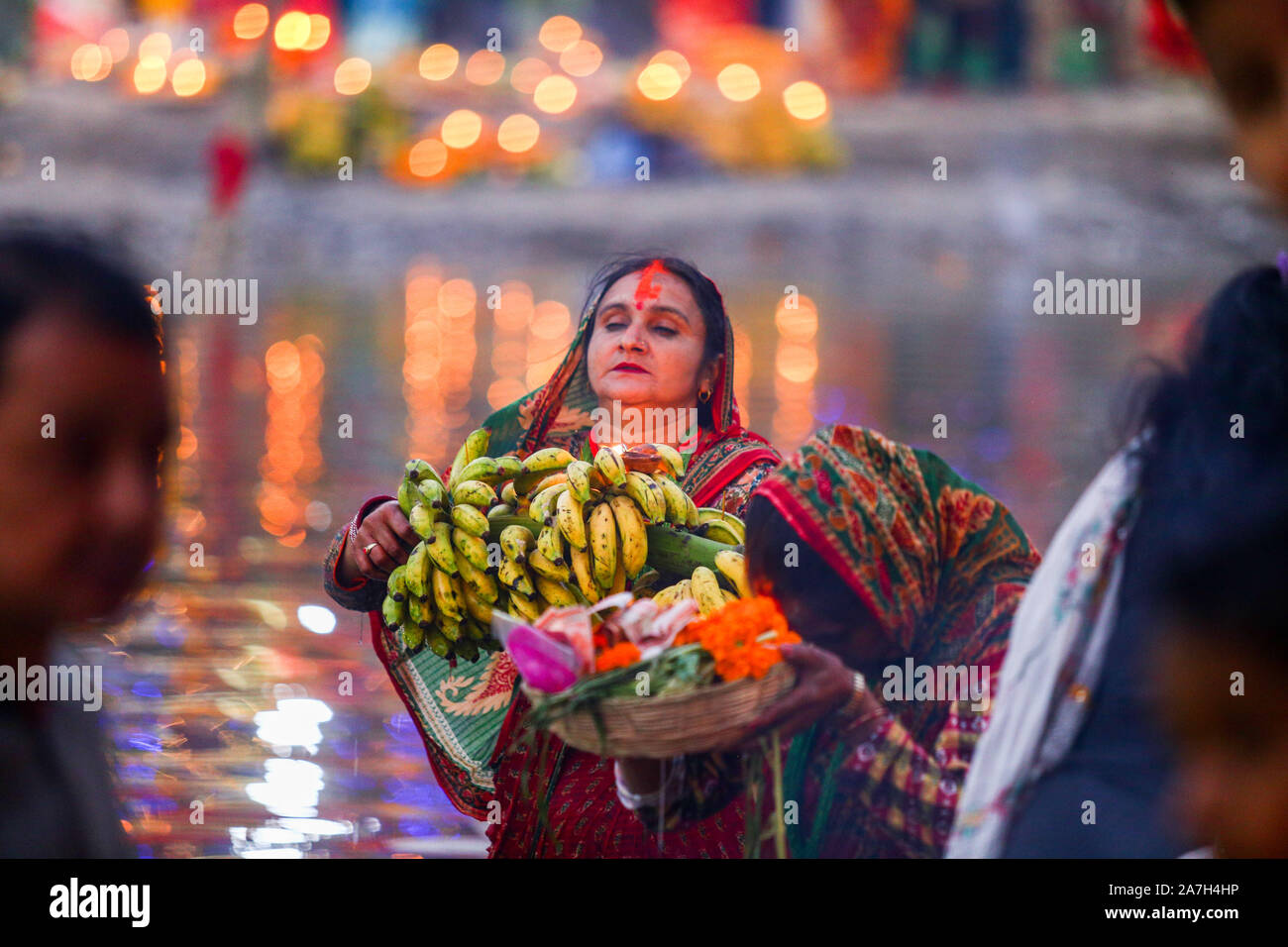 A hindu devotee stands at the Bagmati river to offer prayers to setting ...
