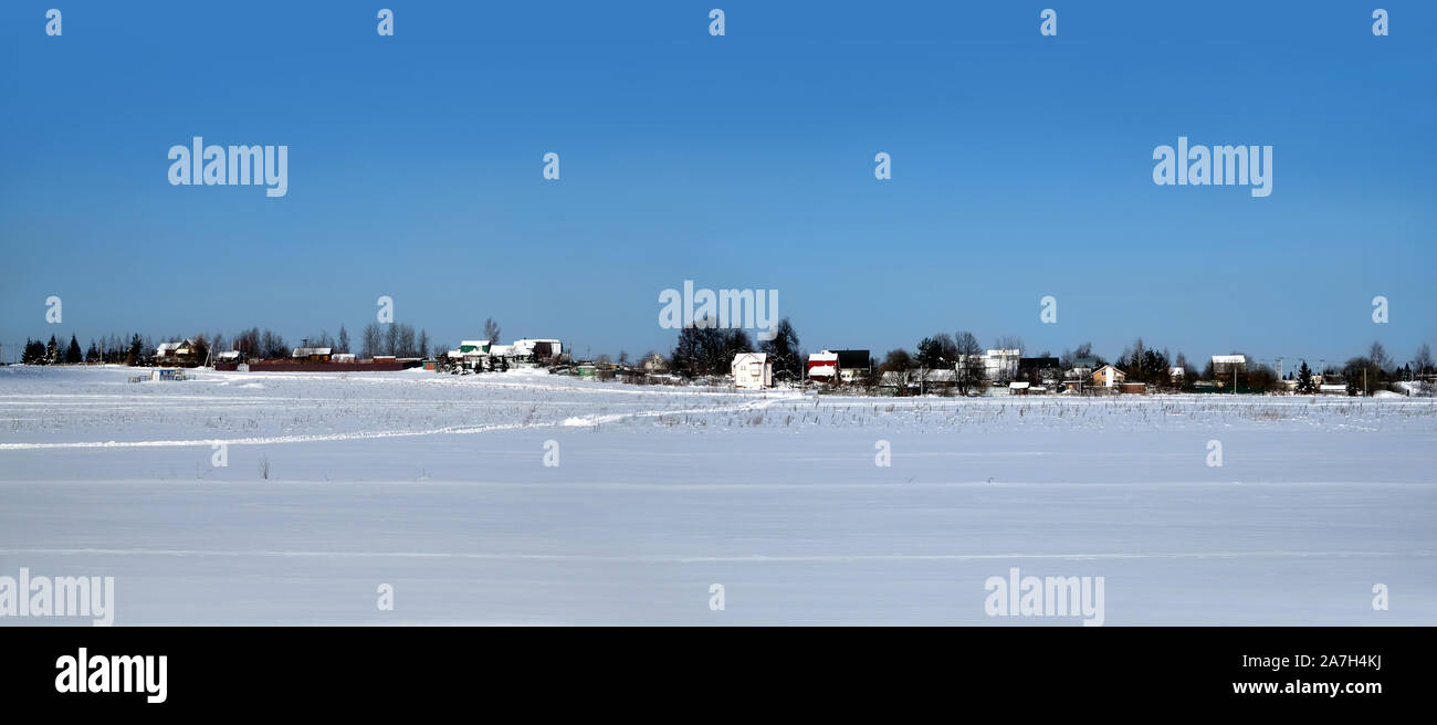 Beautiful rural landscape with a village on skyline after snow field ...