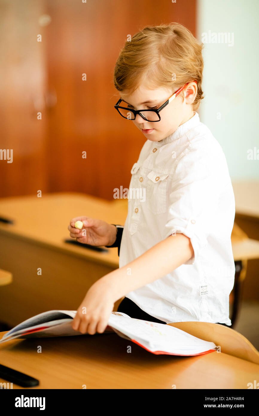 Seven years old child with glasses writing his homework at school. Boy ...