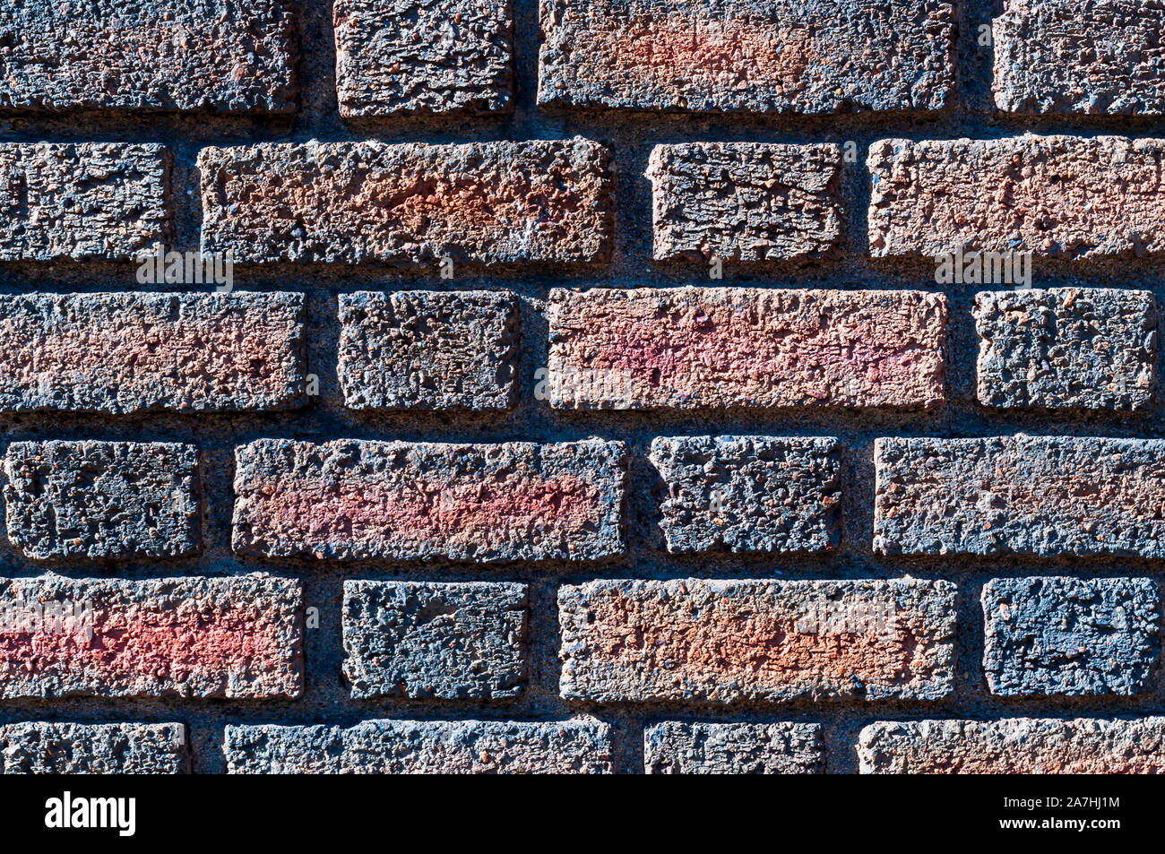 A weathered brick wall with bricks of various sizes and multi colored ...