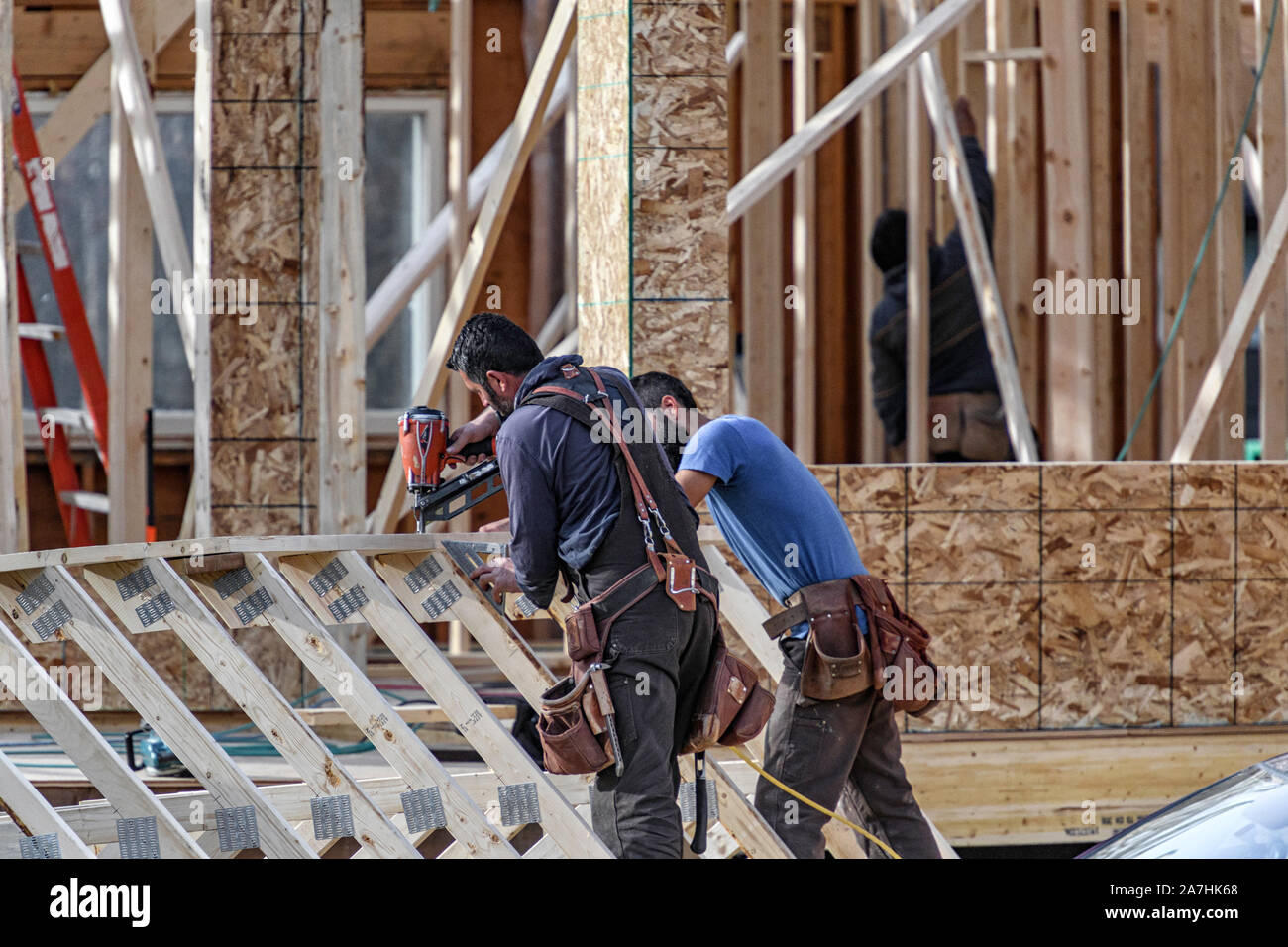 Housing construction workers installing roof trusses on a new home ...