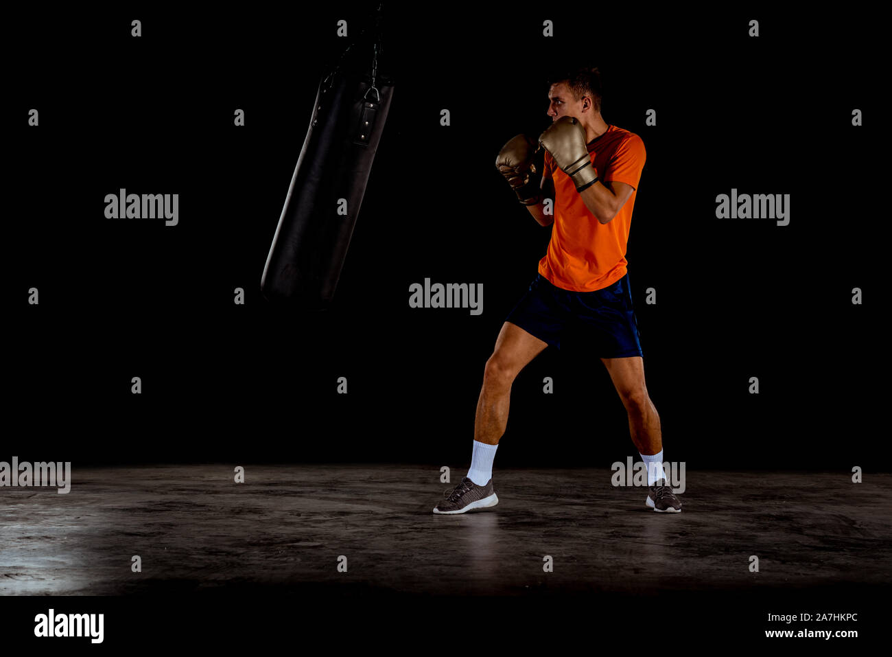 Silhouette male boxer hitting a huge punching bag at a boxing studio ...