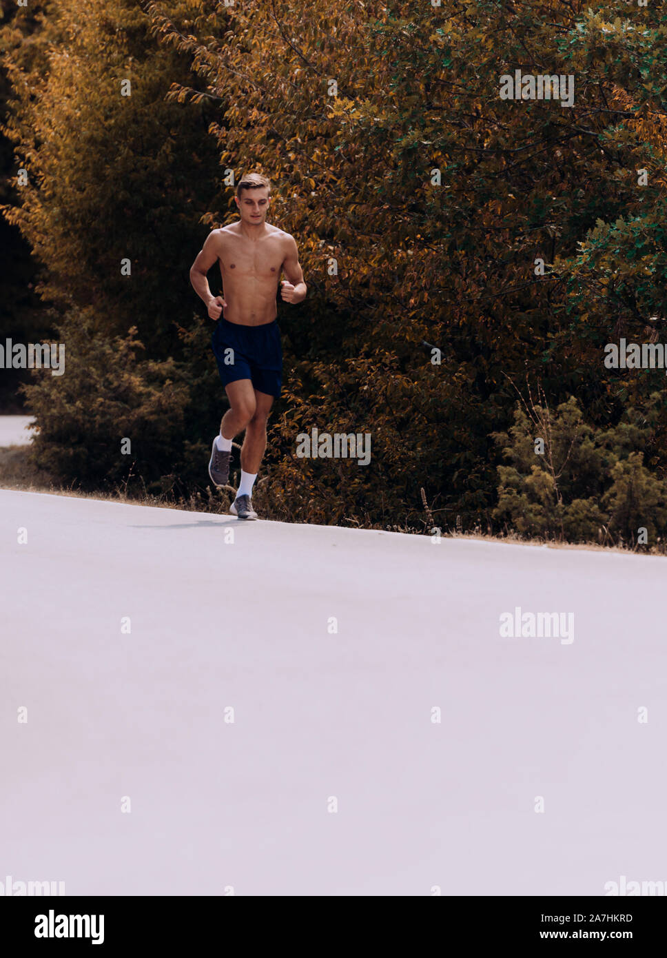 Sweaty shirtless man running on rural road. Hispanic male athlete ...