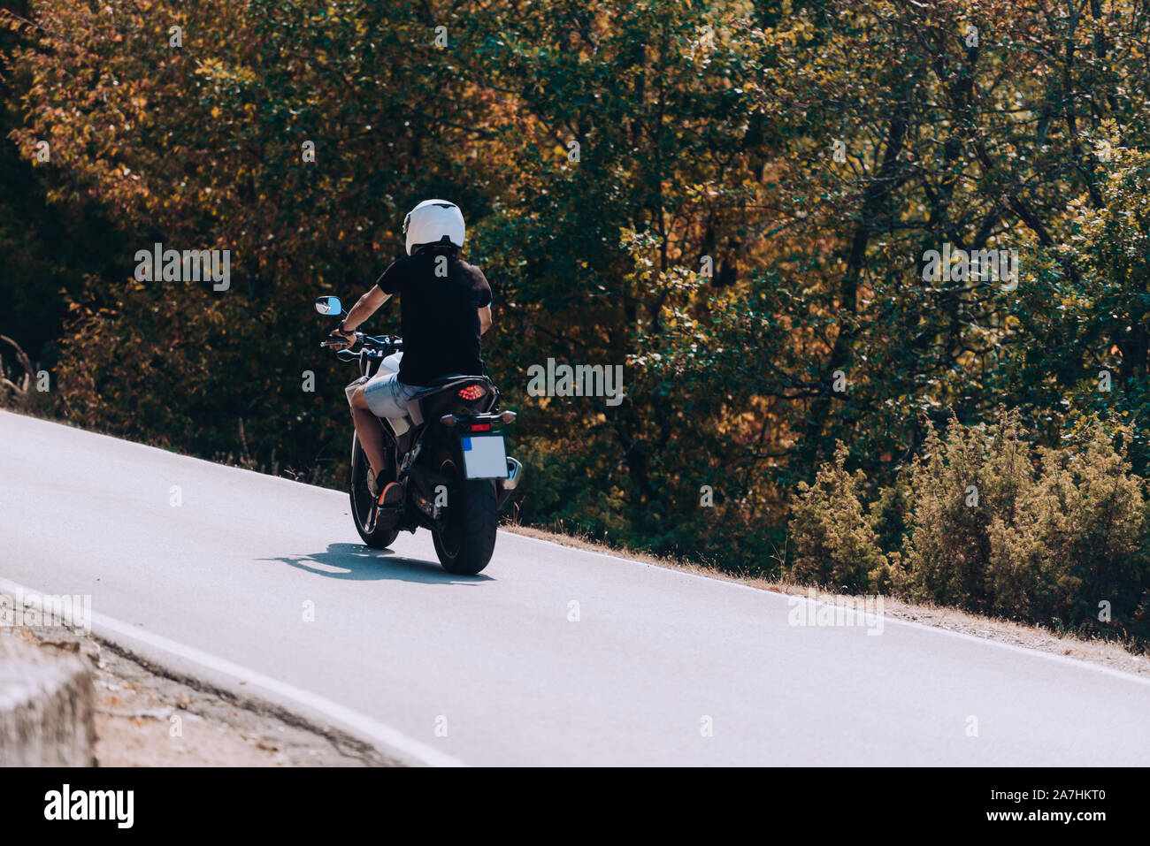 Driver riding motorcycle on an empty asphalt road on the mountain Stock ...