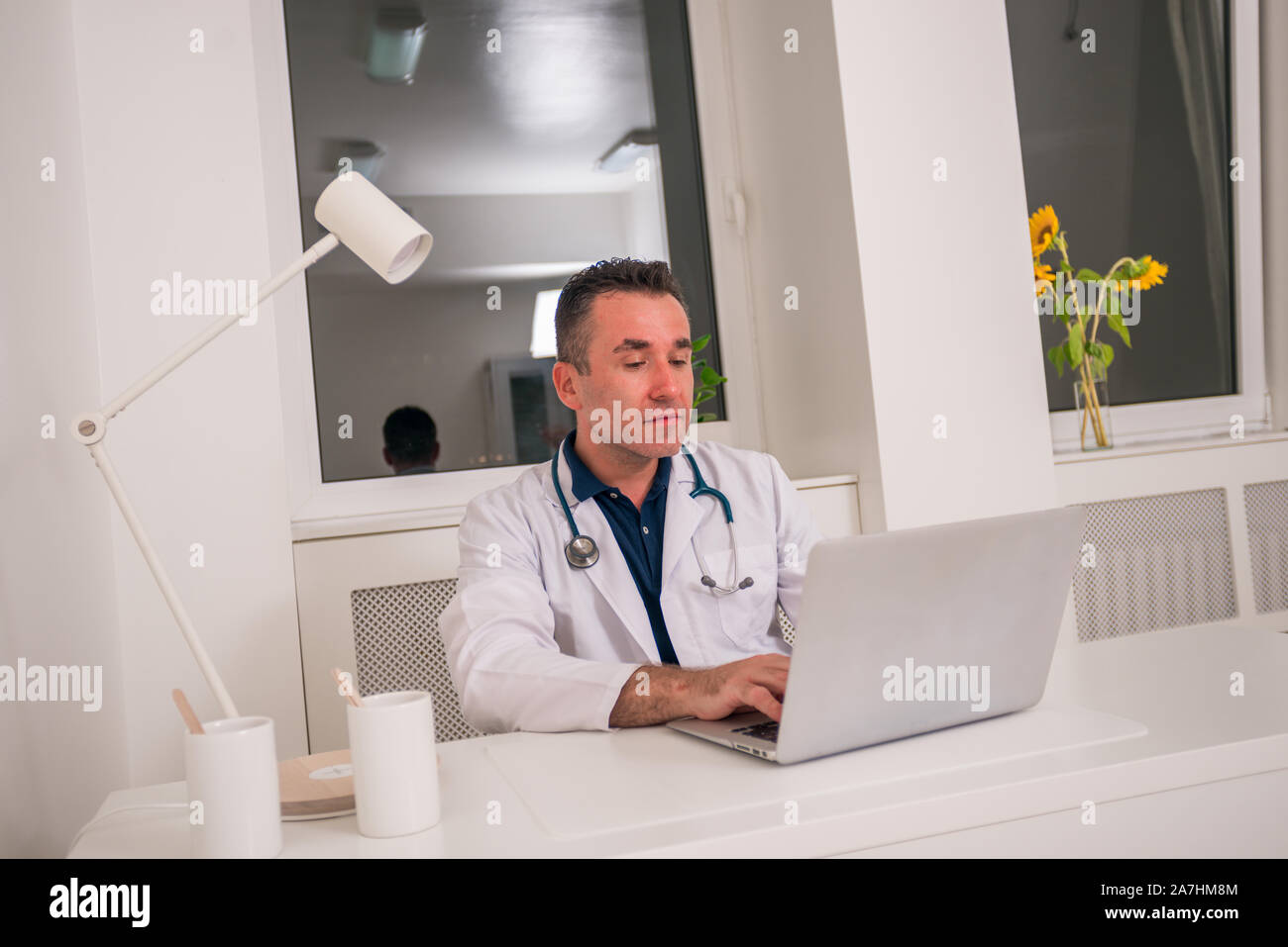Portrait of Doctor specialist sitting on a chair at his desk while ...