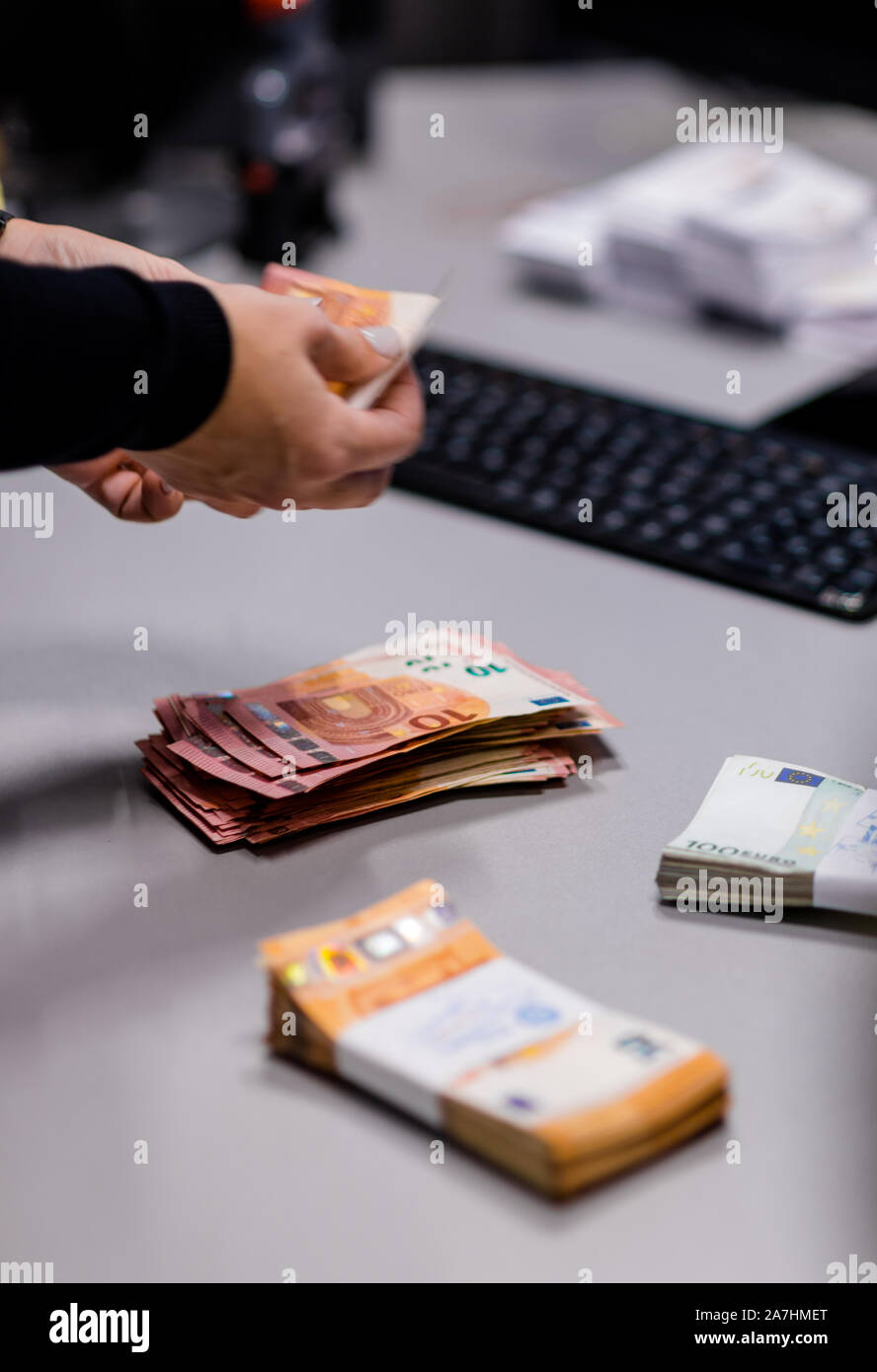 Office worker arranging bundles of euro € cash on the counting desk ...
