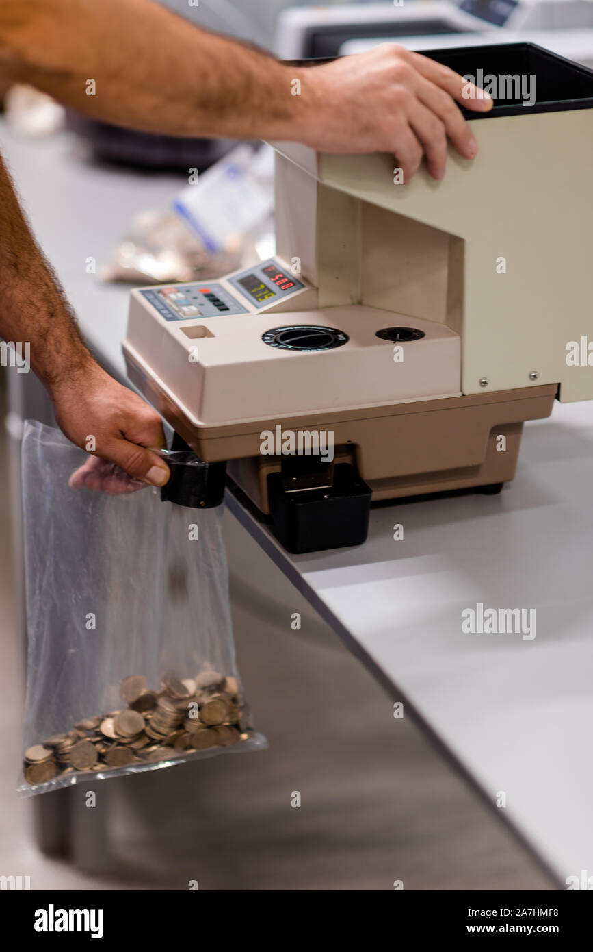 Man filling a plastic bag with metal coins after counting them on a ...
