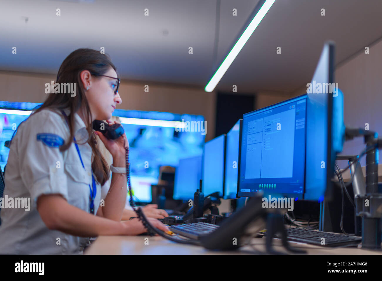 Female security guard operator talking on the phone while watching the ...