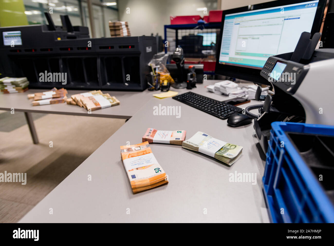 Bundles of euro € cash next to an office desktop computer on the ...