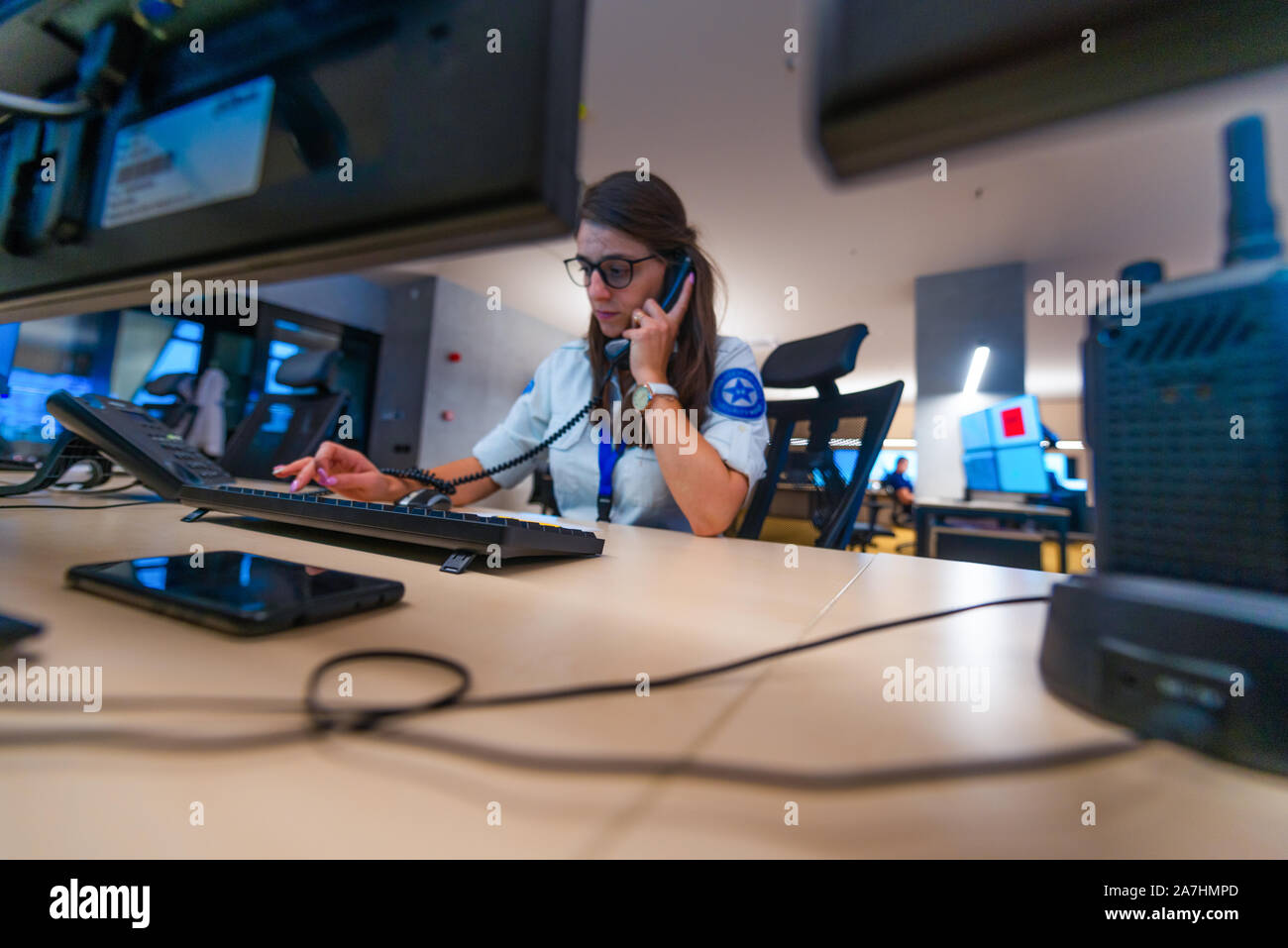 Female security guard operator talking on the phone while watching the ...