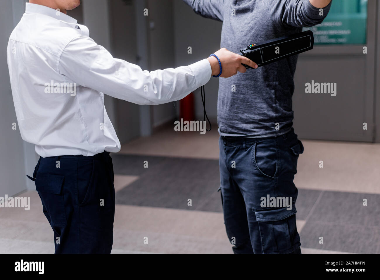 Guard with a metal detector checking a man for weapons and metal ...