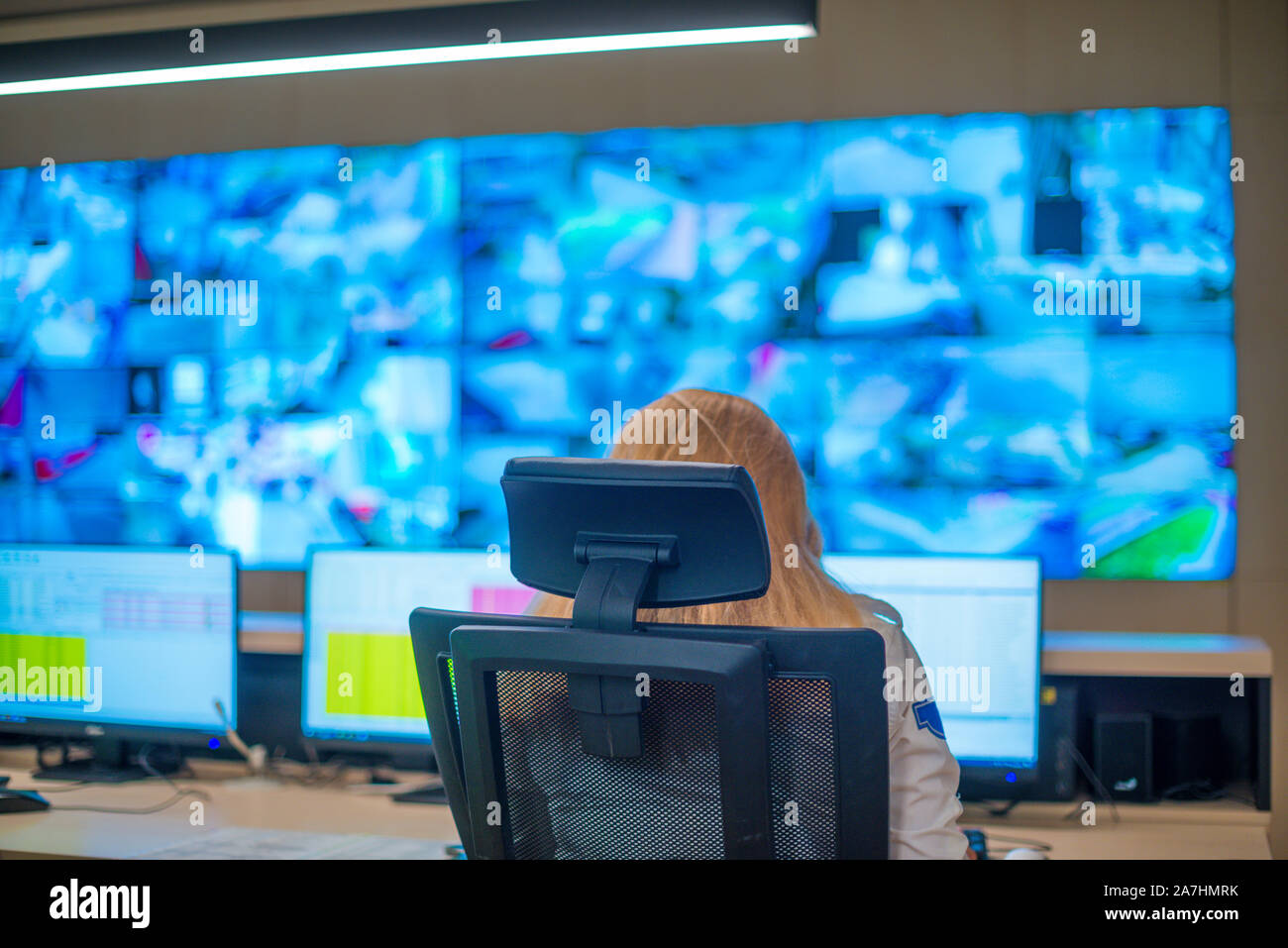 Female security guard sitting back and monitoring modern CCTV cameras ...