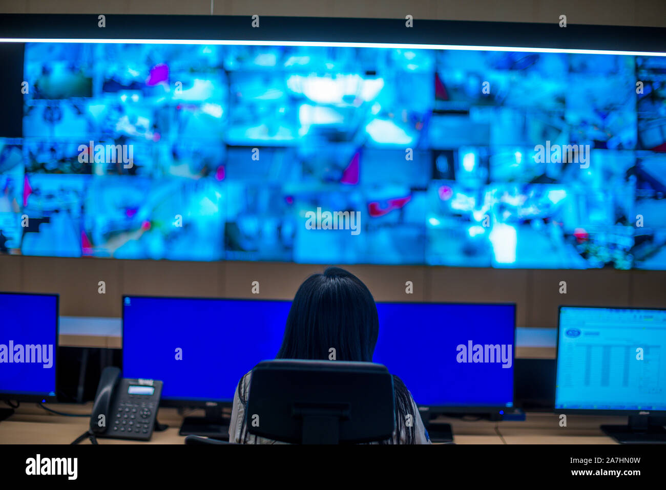 Female security guard sitting back and monitoring modern CCTV cameras ...