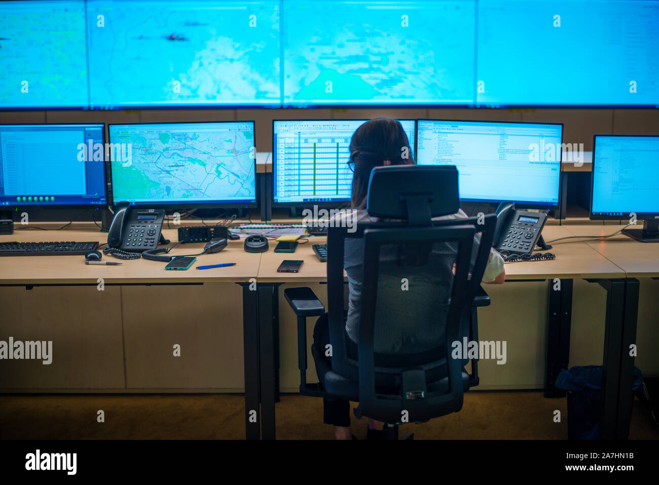 Female security guard sitting back and monitoring modern CCTV cameras ...