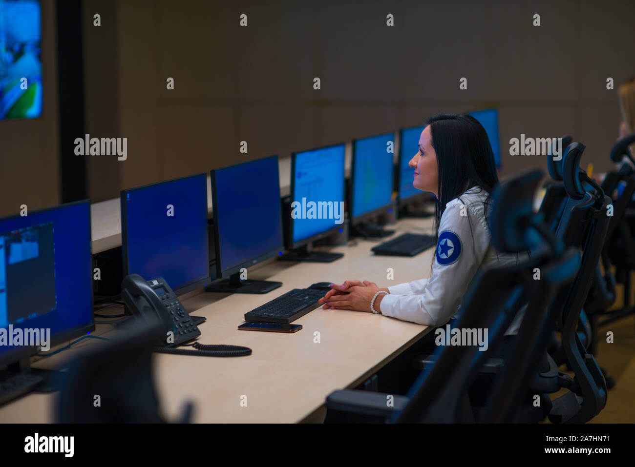 Female security guard sitting and monitoring modern CCTV cameras in a ...