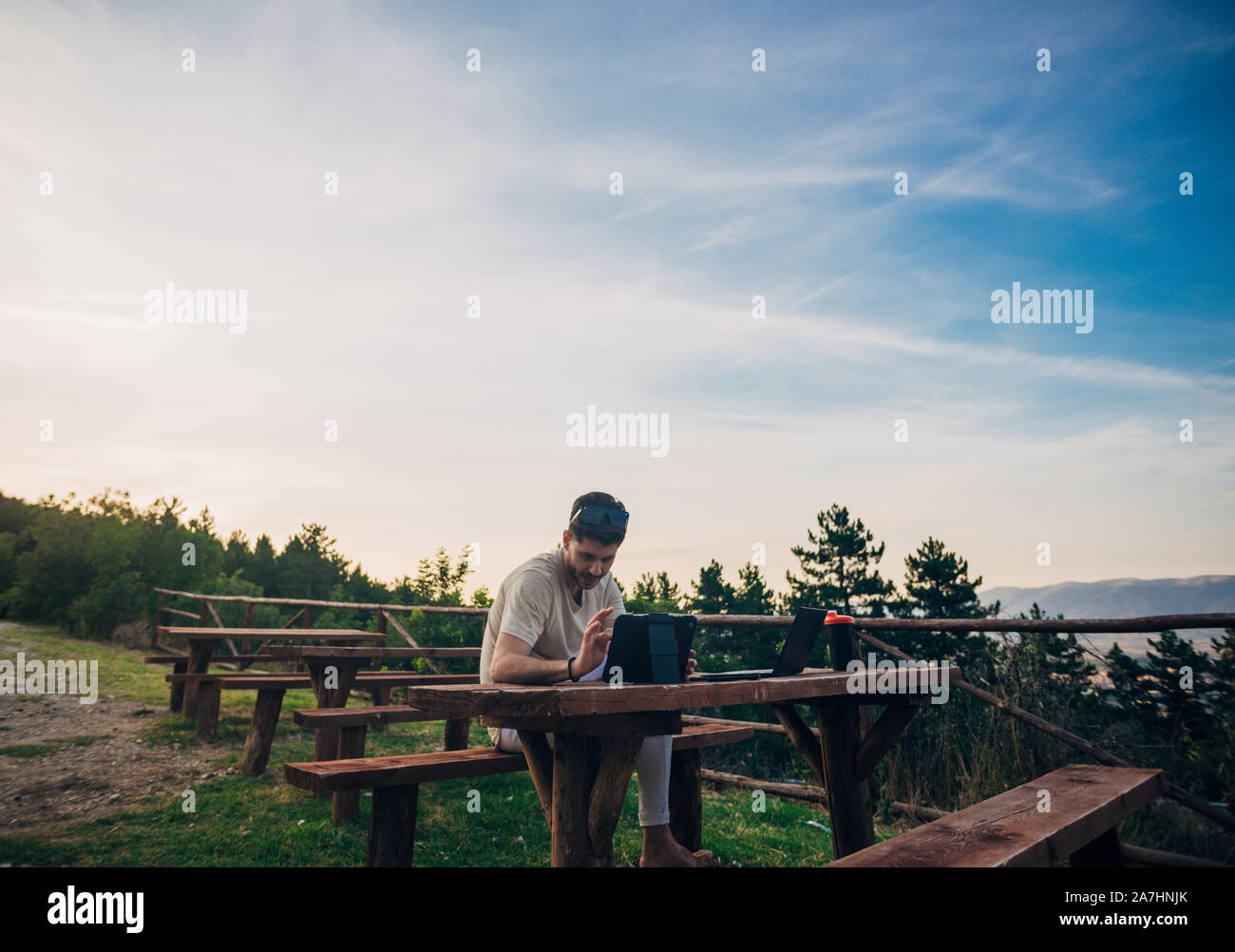 Concentrate man sitting by the table with laptop computer and mobile on ...