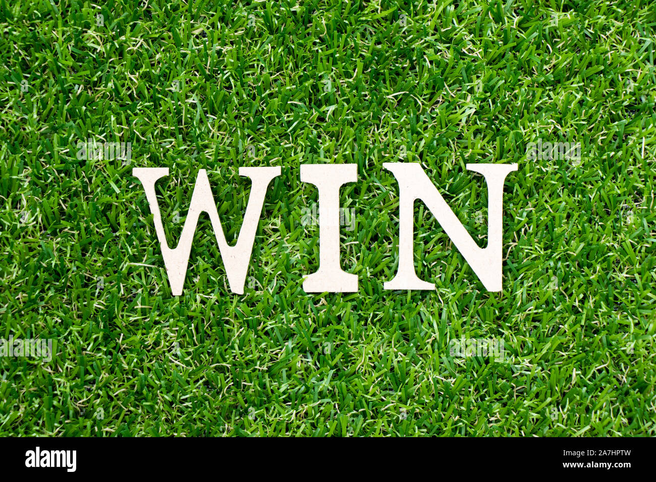 Wood letter in word win on green grass background Stock Photo - Alamy