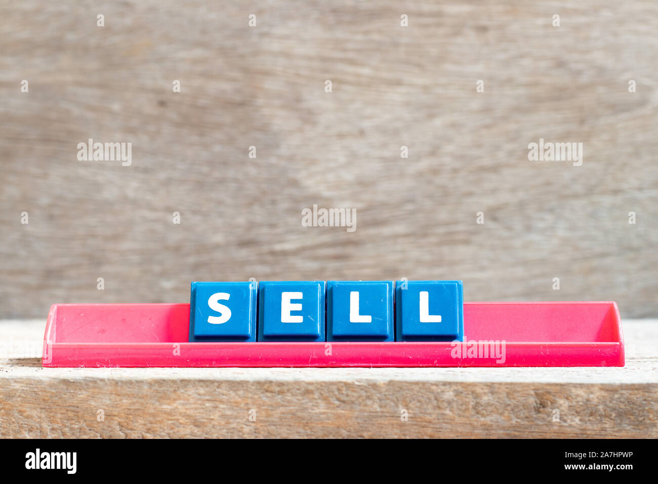 Tile letter on red rack in word sell on wood background Stock Photo - Alamy