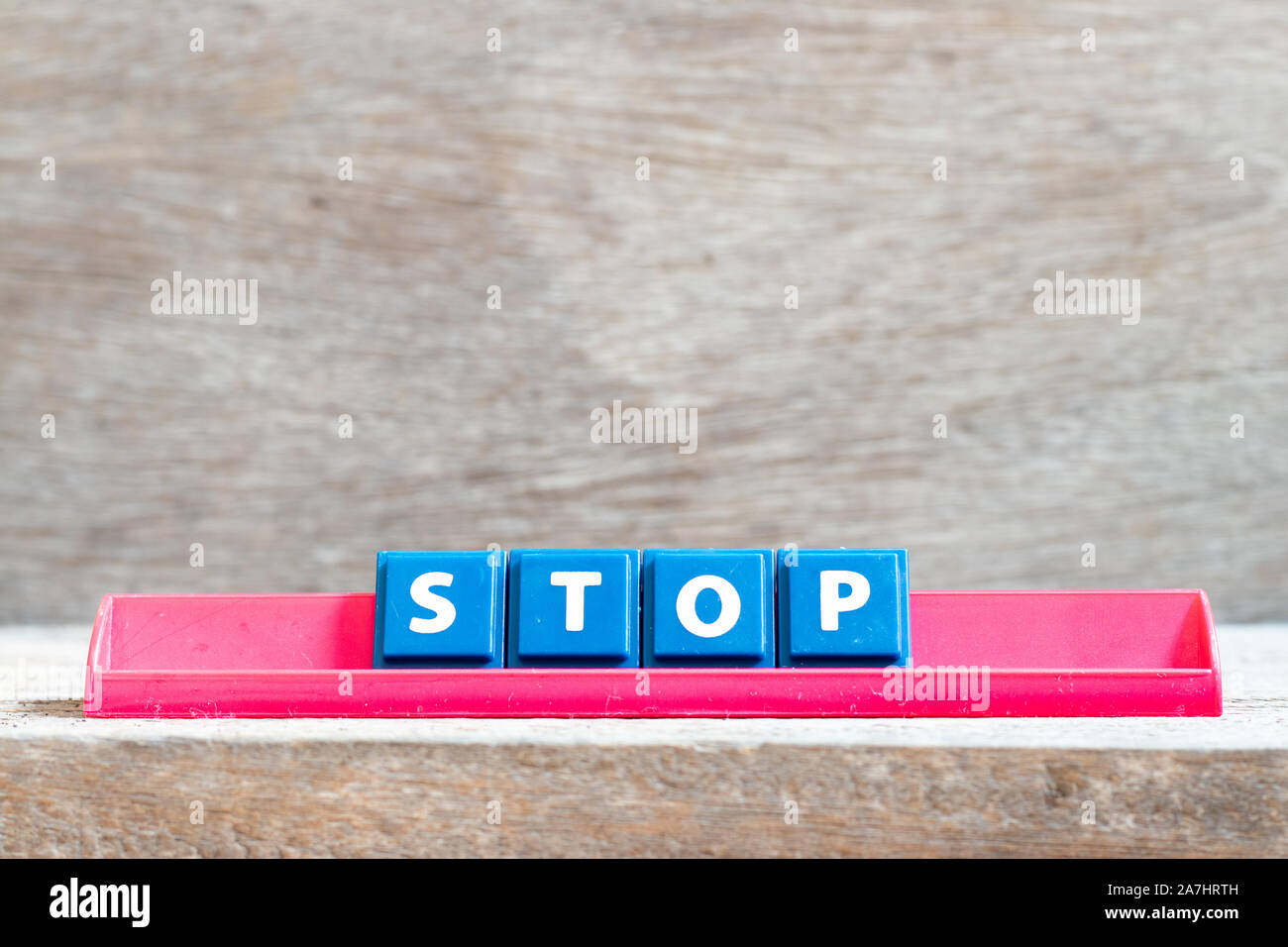 Tile letter on red rack in word stop on wood background Stock Photo - Alamy