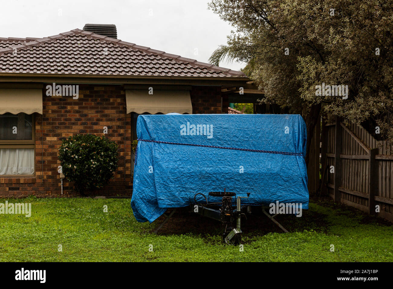 Small caravan covered in blue tarpaulin to protect its surface Stock ...