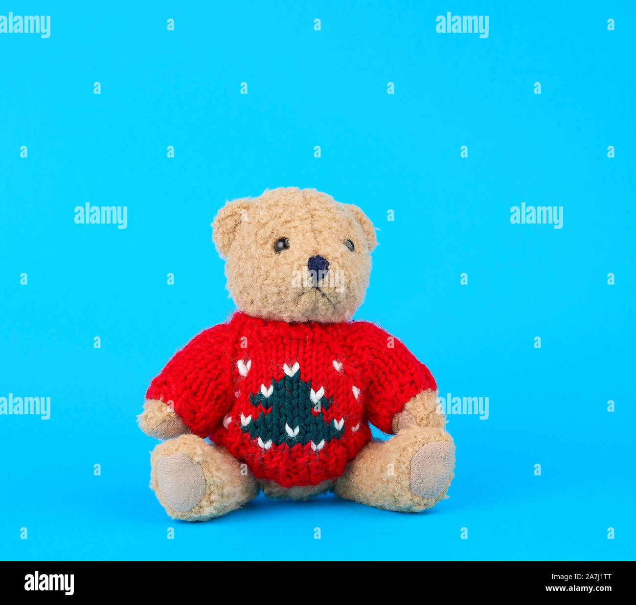 traditional toy teddy bear dressed in a red knitted sweater sits on a ...