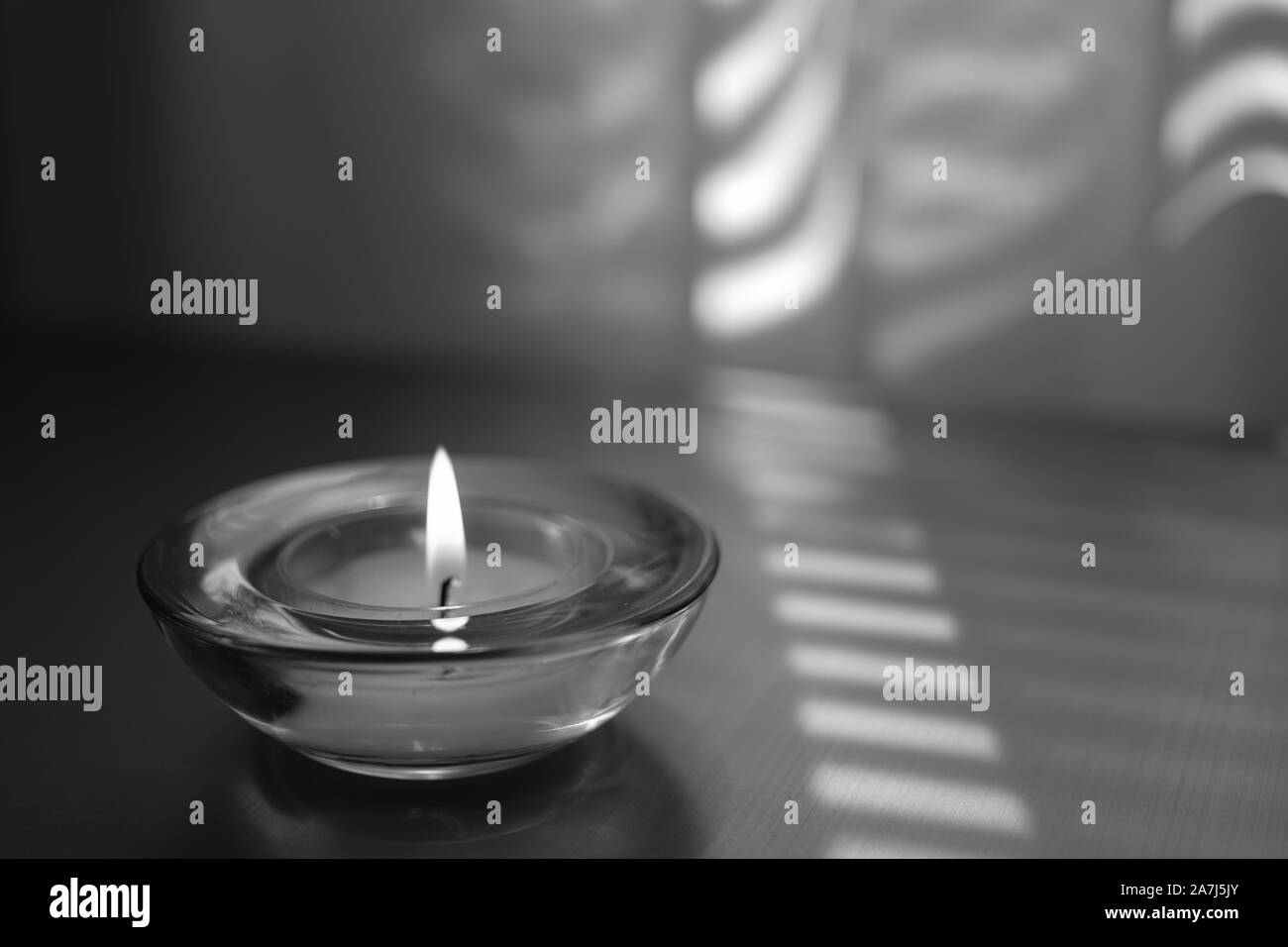 low candle burns in a round glass candlestick, bw photo Stock Photo - Alamy