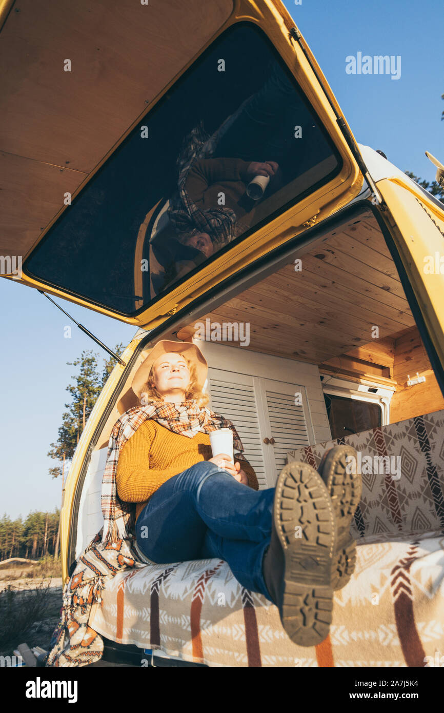 Young blonde Caucasian woman relaxing in yellow camper van during ...