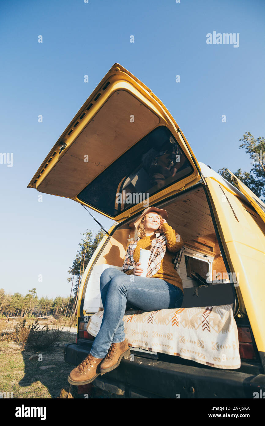Young blonde Caucasian woman relaxing in yellow camper van during ...
