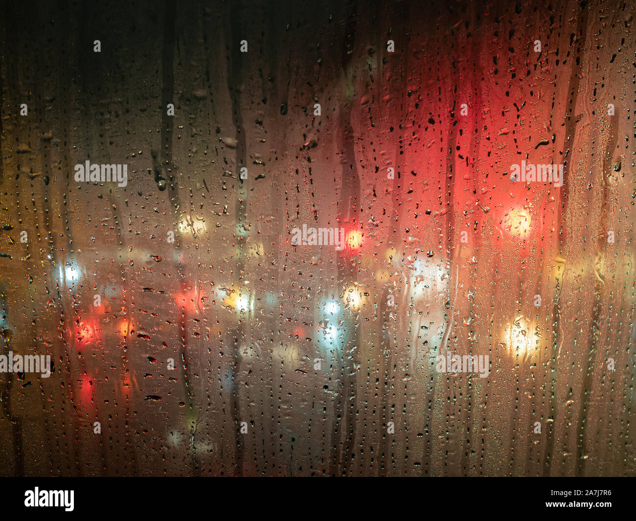 Raindrops on a bus window with blurred headlights behind Stock Photo ...