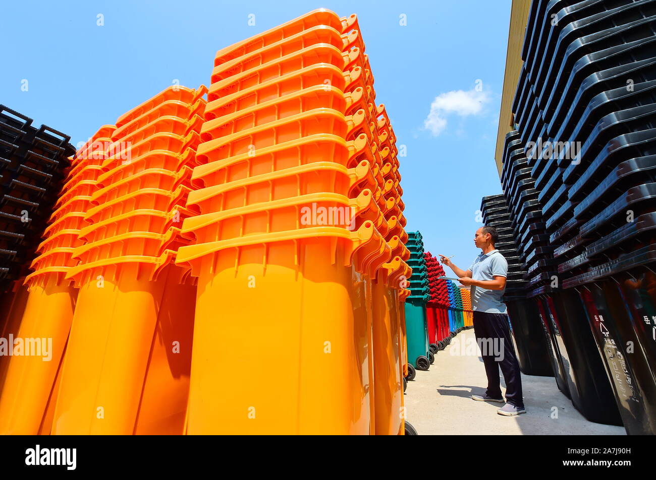 A staff works to orderly store trash bins in a warehouse in Huichang ...