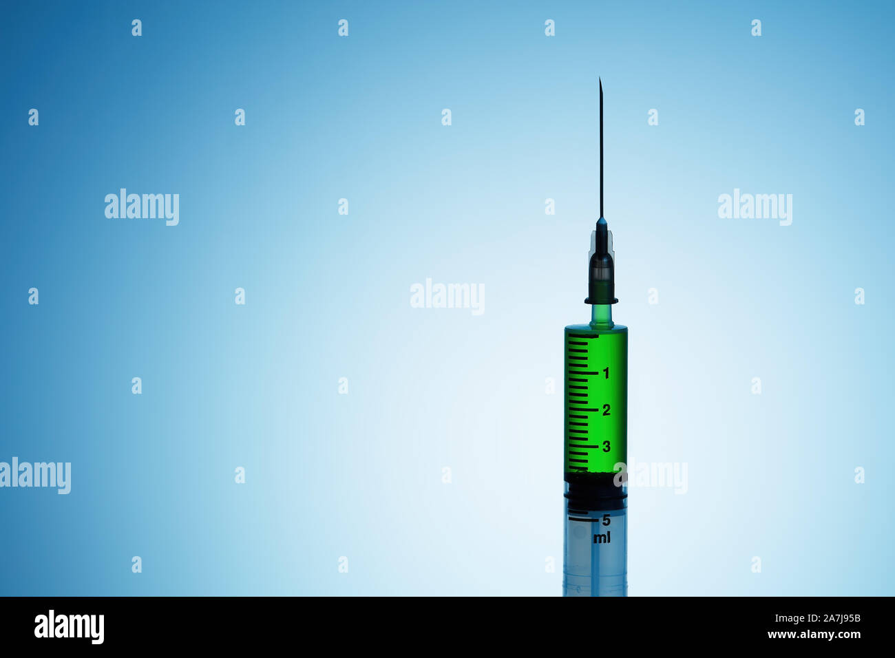 Syringe filled with green liquid on blue background Stock Photo - Alamy