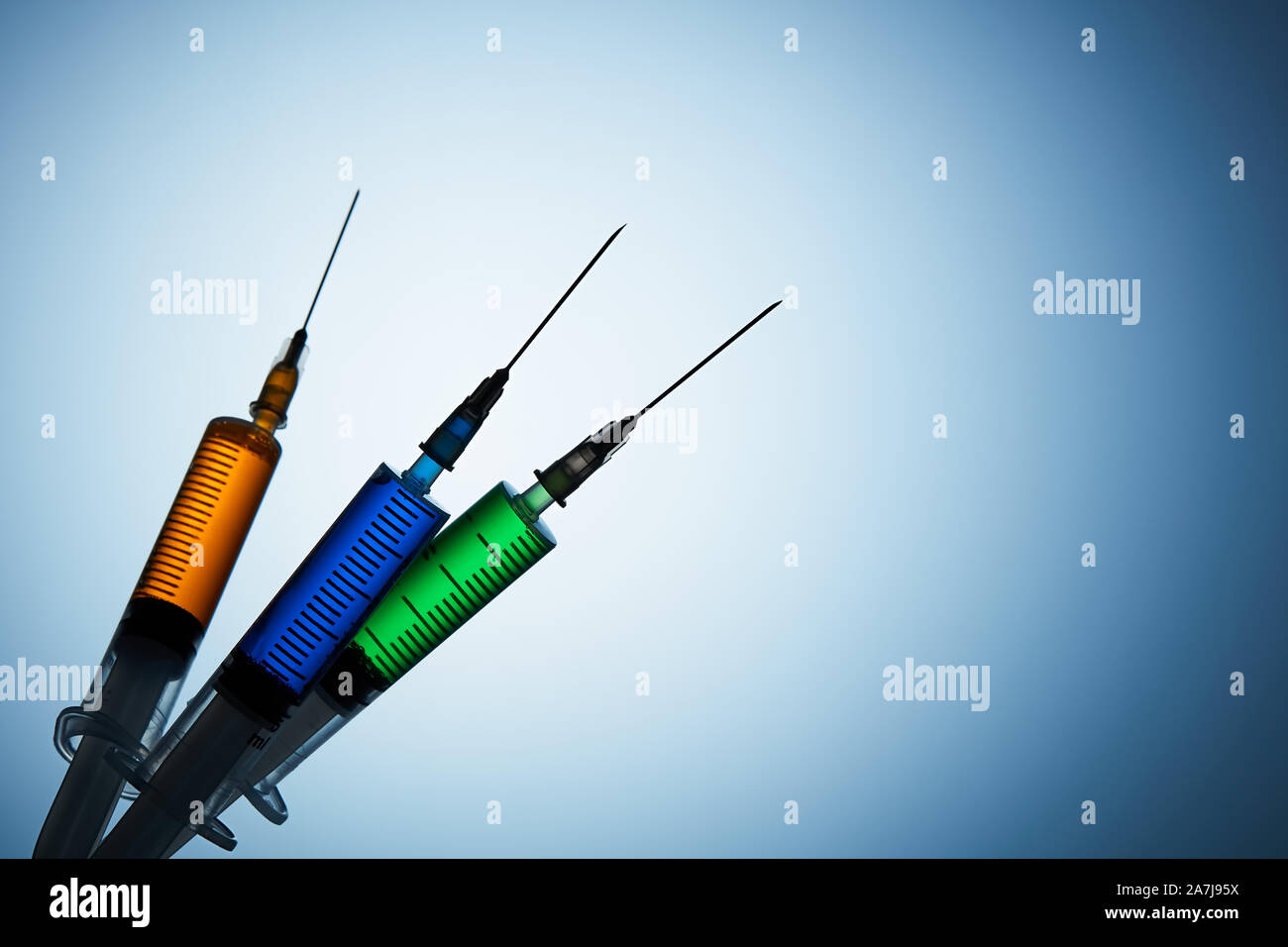 Three syringes filled with colorful liquids on blue background Stock ...