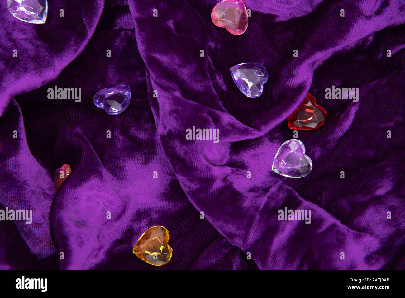 Glass colored hearts on a purple velvet background Stock Photo - Alamy