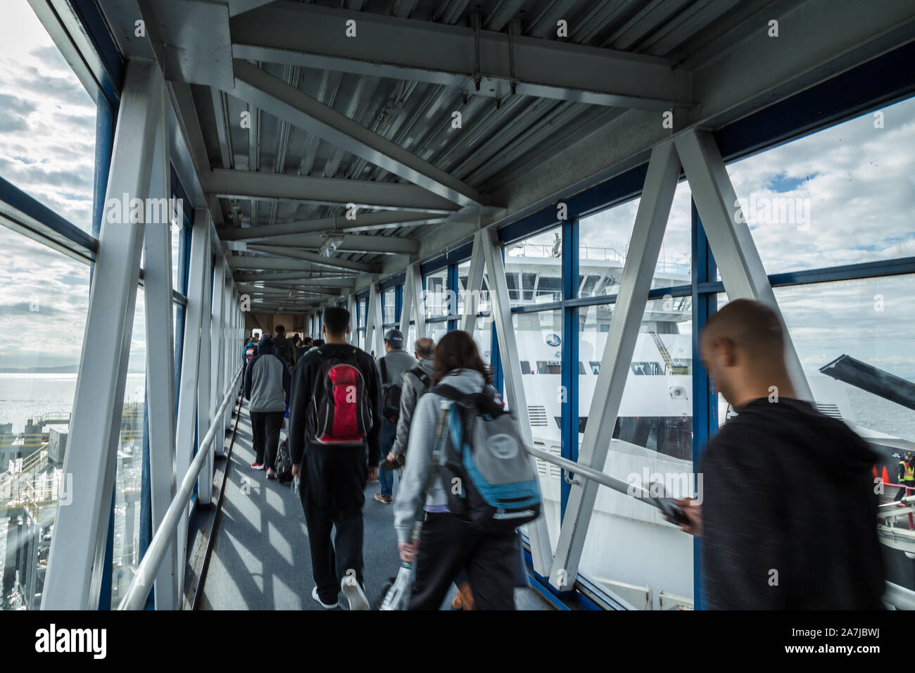 A passenger ferry terminal gangway with travellers walking with their ...