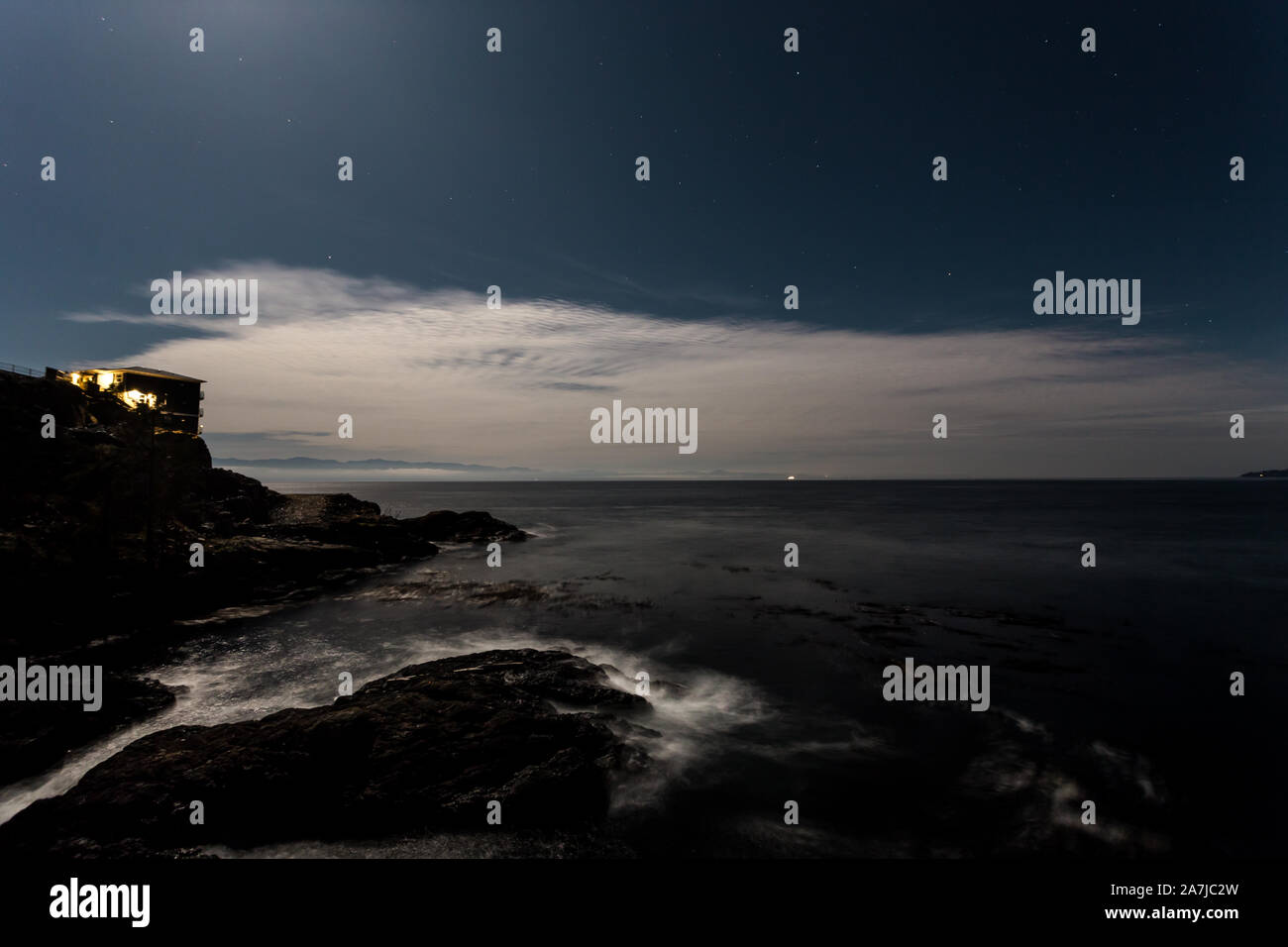 Night time view of a cliffside ocean view with a starry night sky and ...