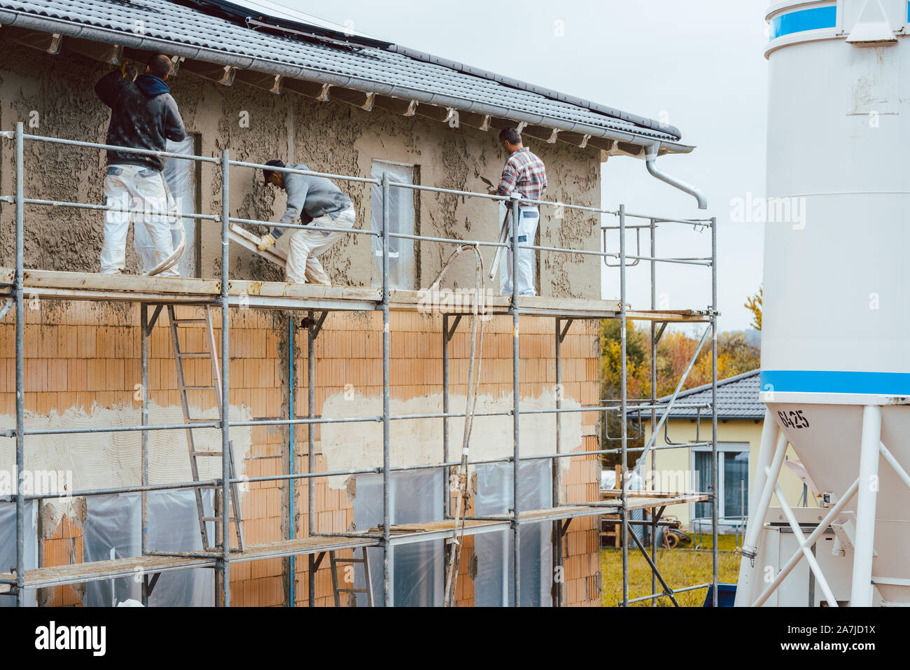 Plaster worker on scaffold working Stock Photo - Alamy