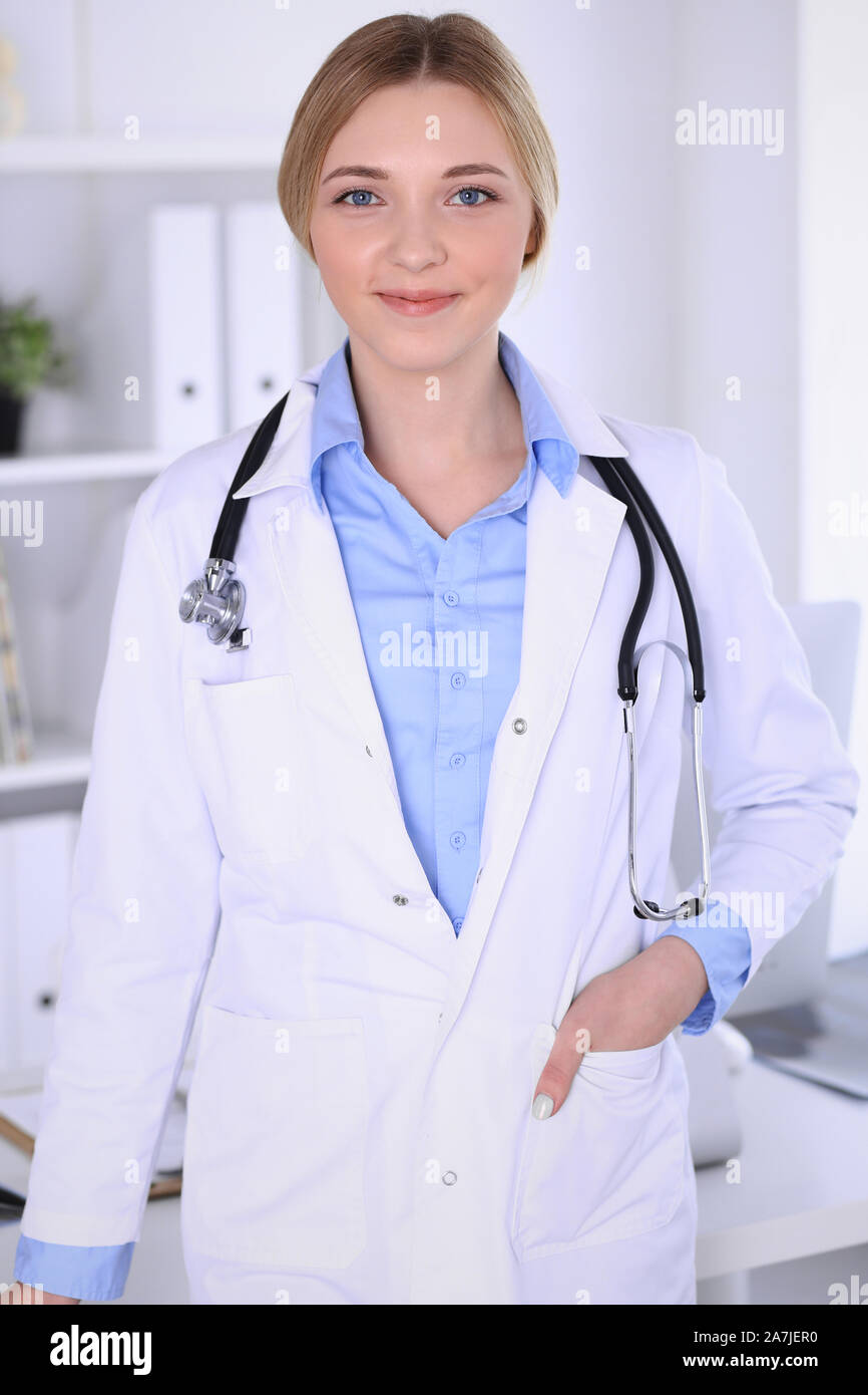 Young woman doctor at work in hospital looking at camera. Khaki colored ...